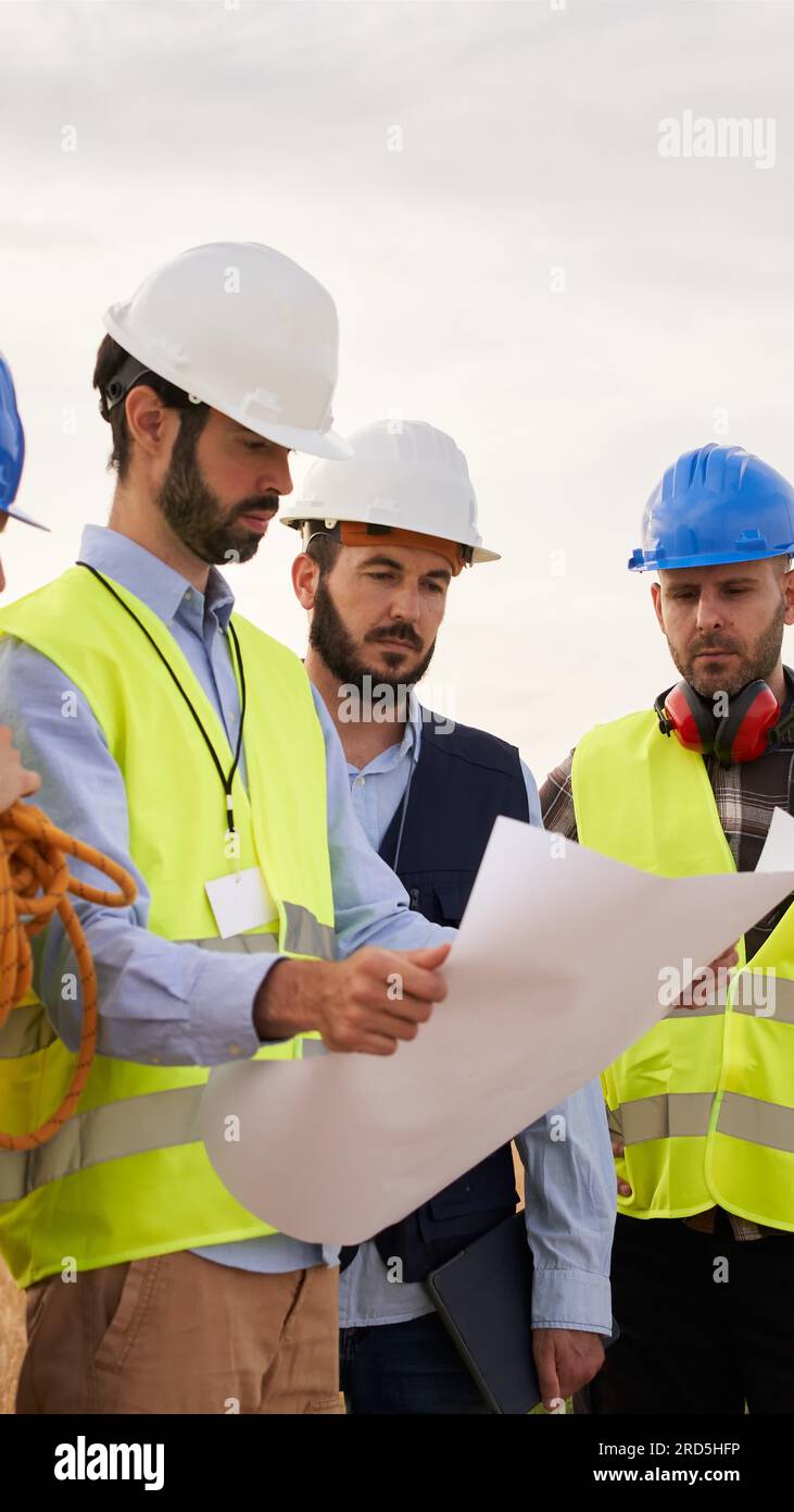 Group of Caucasian engineers check a plan at an air turbine field ...