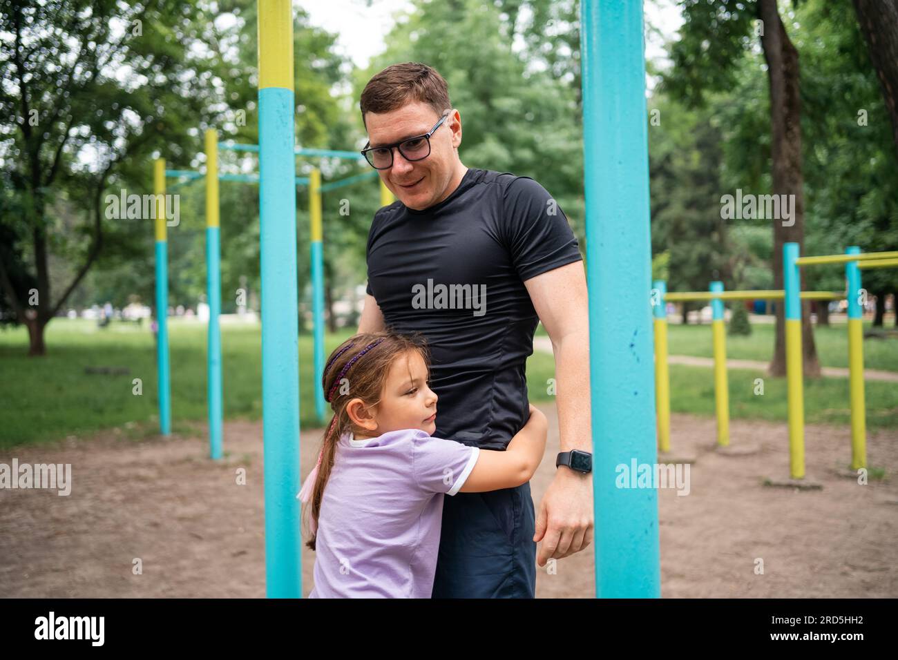 Father with child girl doing pull-ups on workout outdoor area. Healthy ...