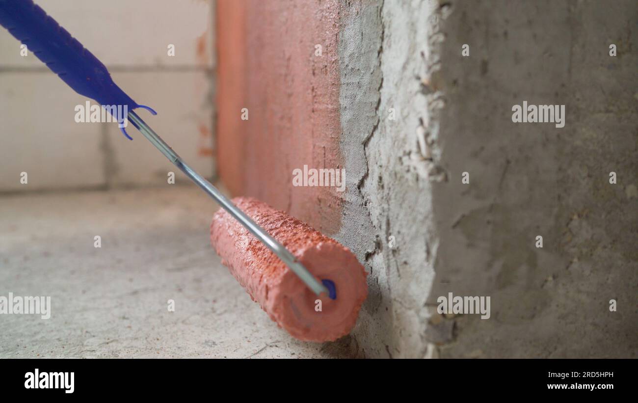 Primer mix pink. Roller with pink paint for wall application. Roller ...
