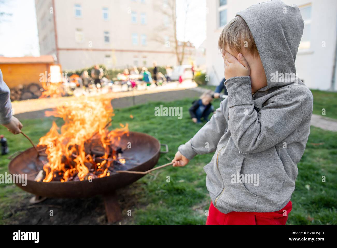Cute little adorable baby boy put big wooden stick in fire pit with ...