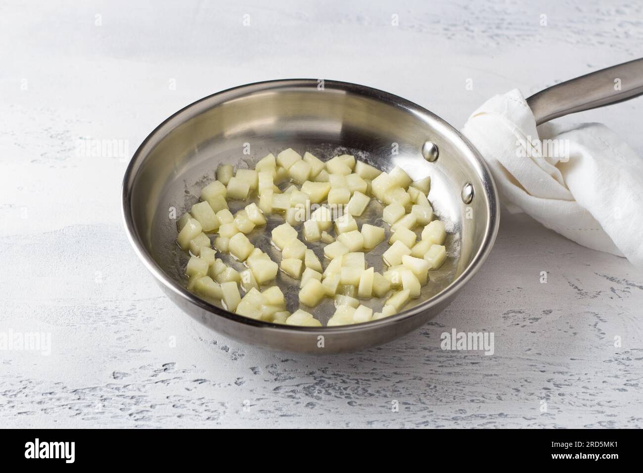 Frying pan with pear stewed in butter on a light blue background ...