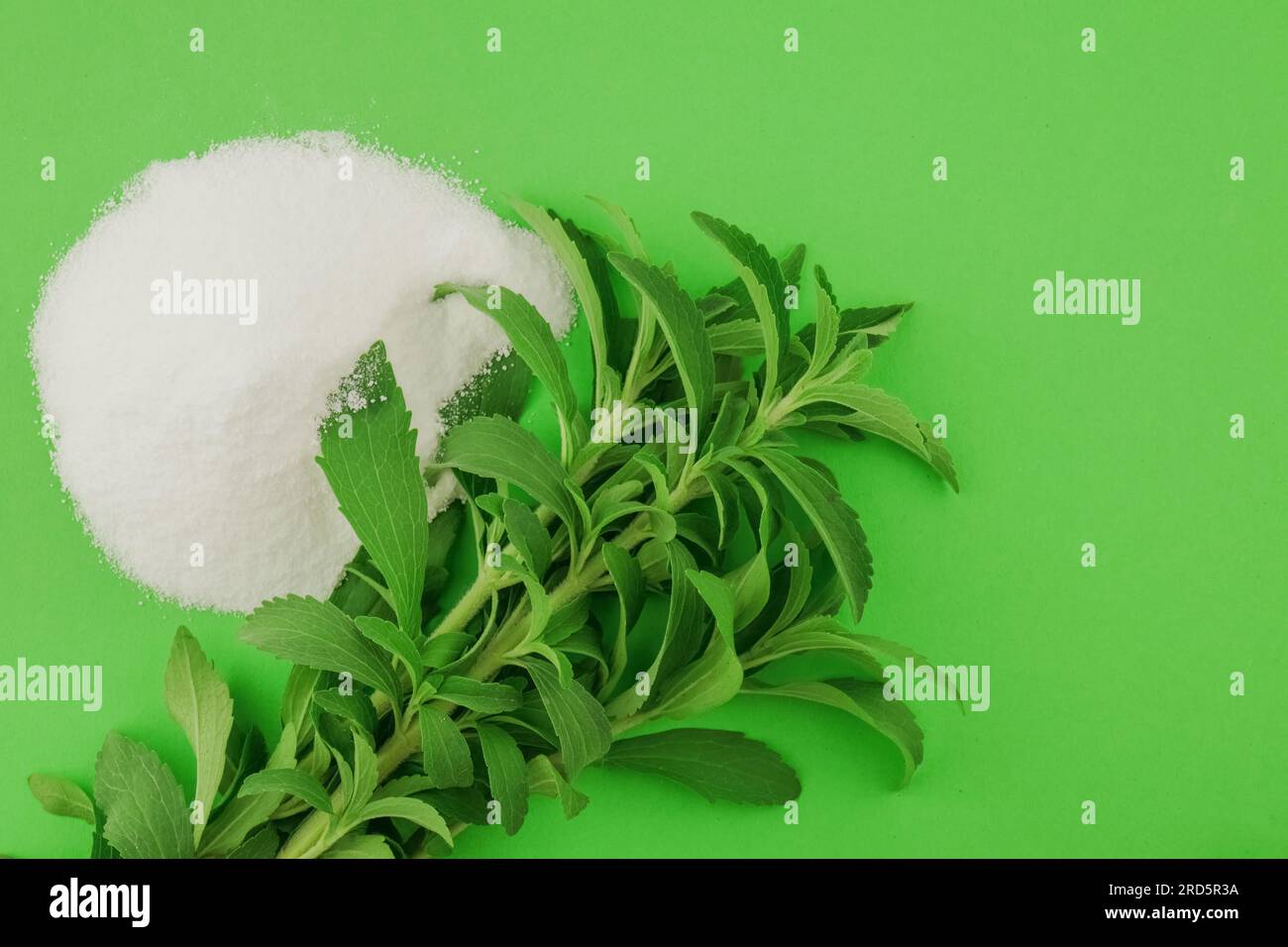 Green stevia and granulated sugar circle on green background.Stevia ...