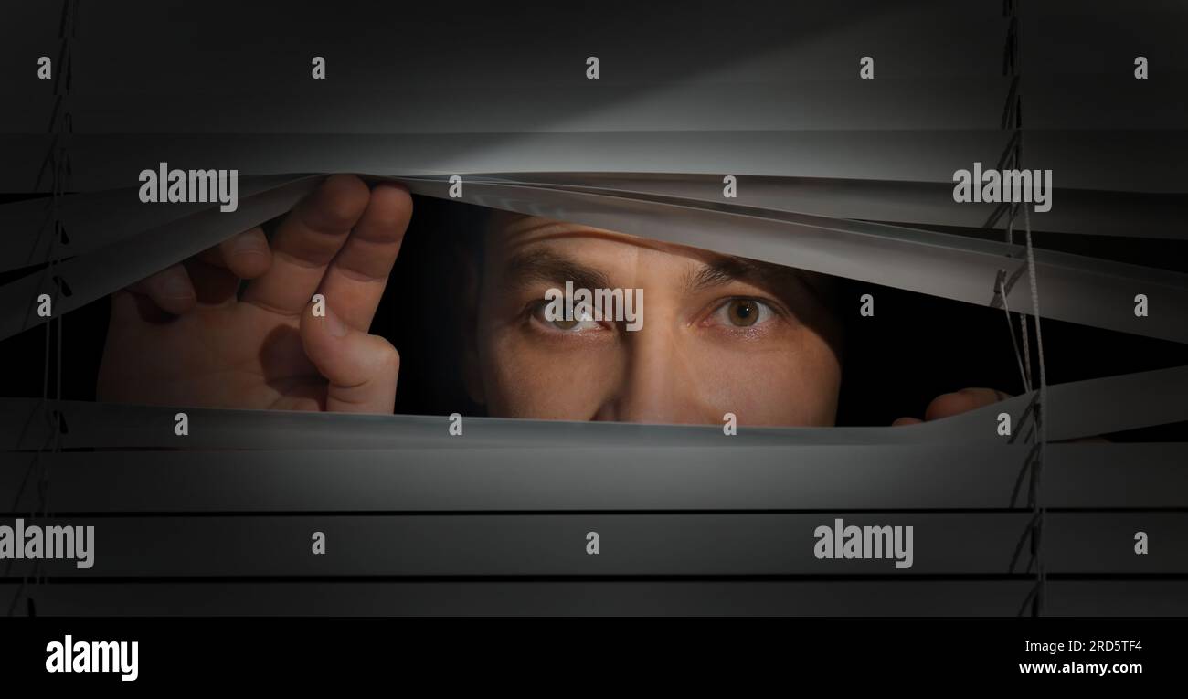 Man looking through window blinds into darkness. Paranoia concept Stock ...