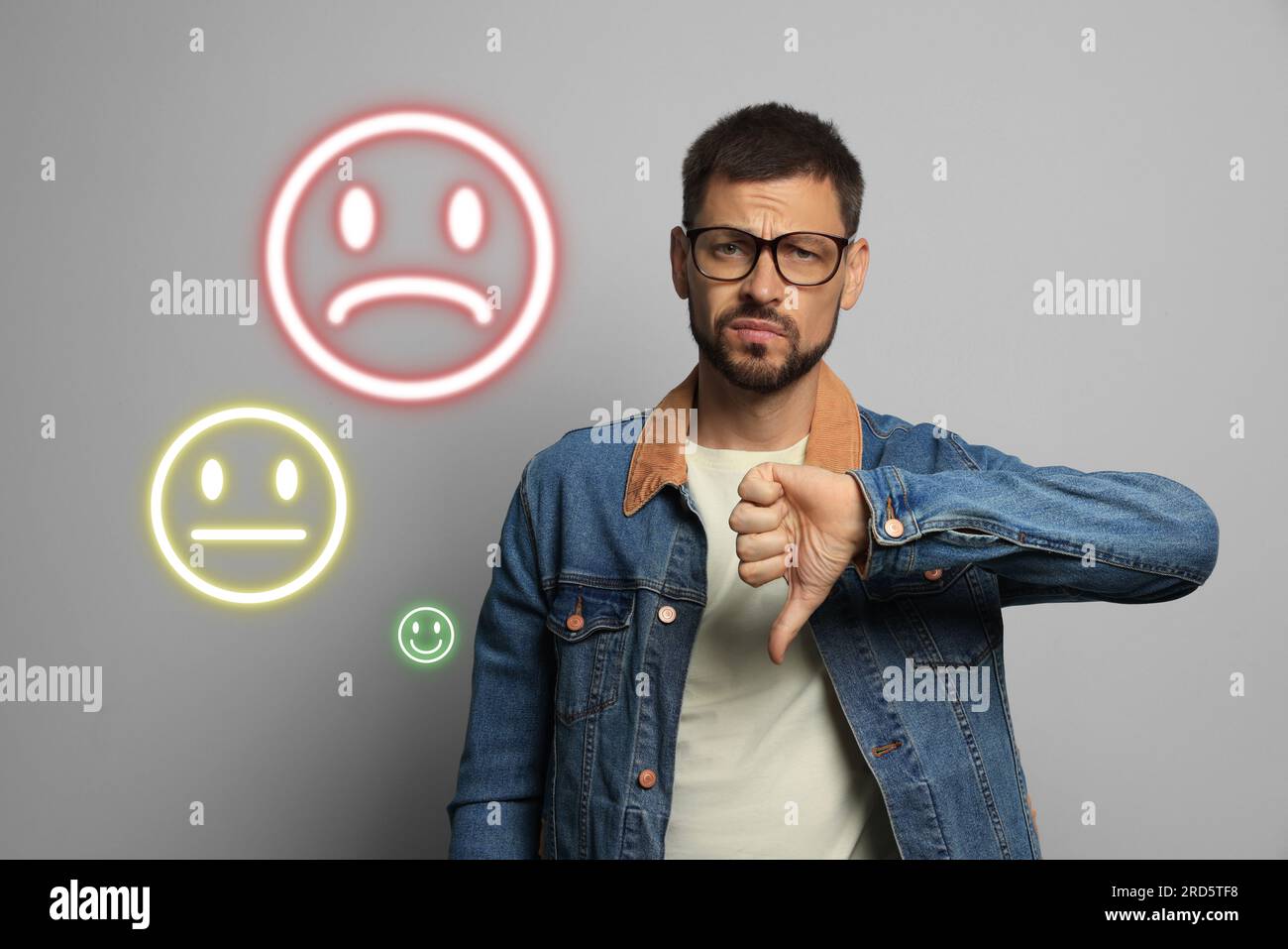 Complaint. Dissatisfied man showing thumbs-down on grey background ...