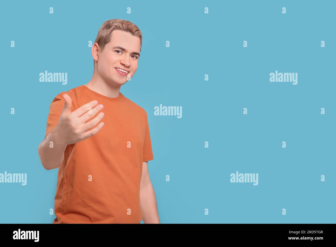 Happy man inviting to come in against light blue background, space for ...