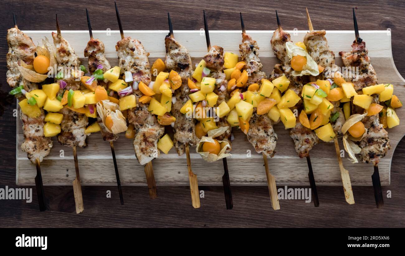 Grilled seasoned chicken skewers topped with golden berry salsa Stock ...