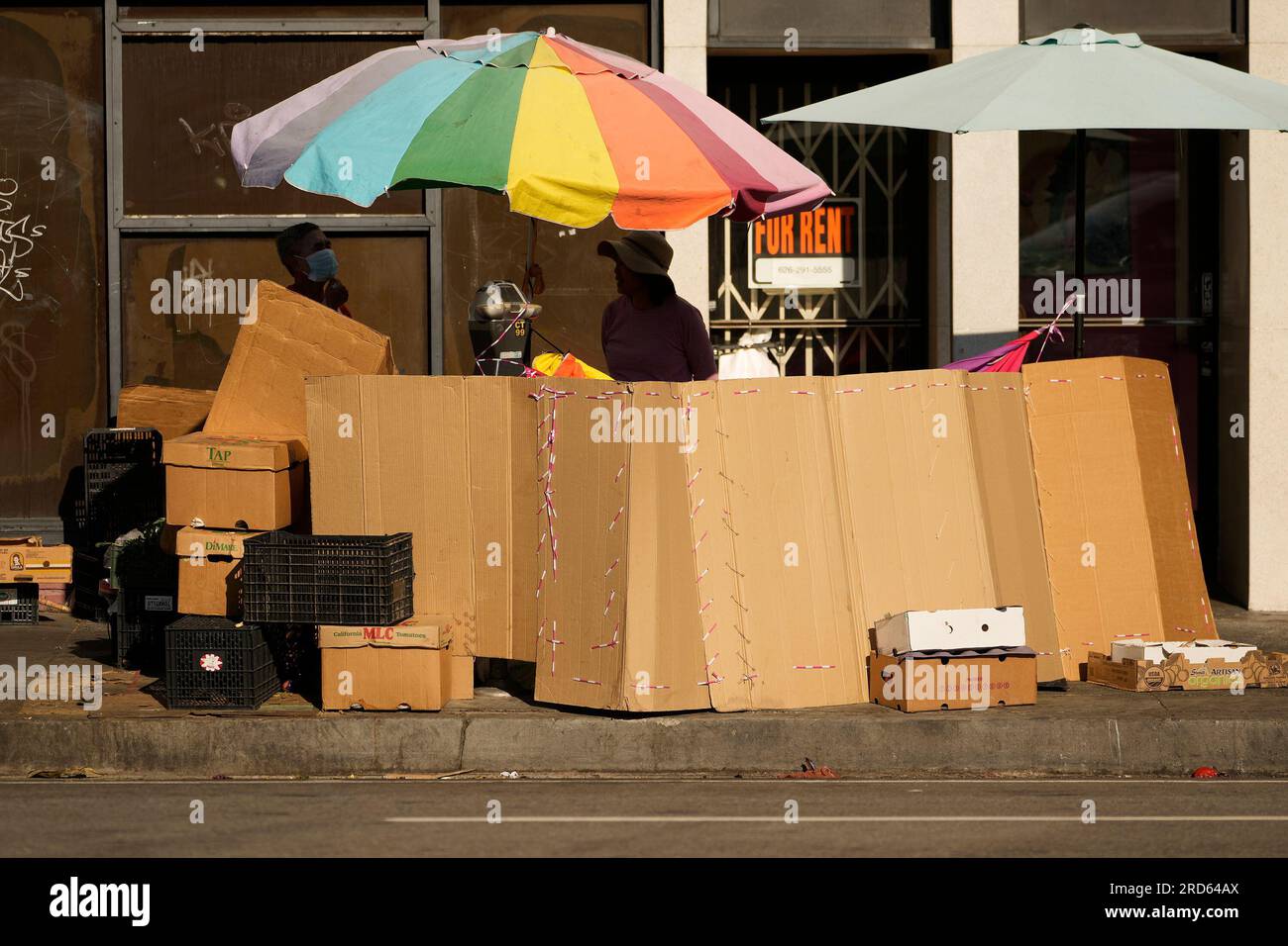 A street vendor erects a cardboard barricade to shield from the extreme ...