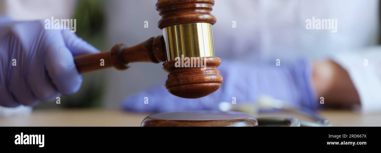 Doctor holds judge gavel in gloved hands close up Stock Photo - Alamy