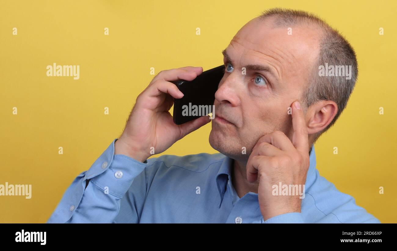 Handsome man 45-55 years old in a blue shirt with a smartphone in his ...