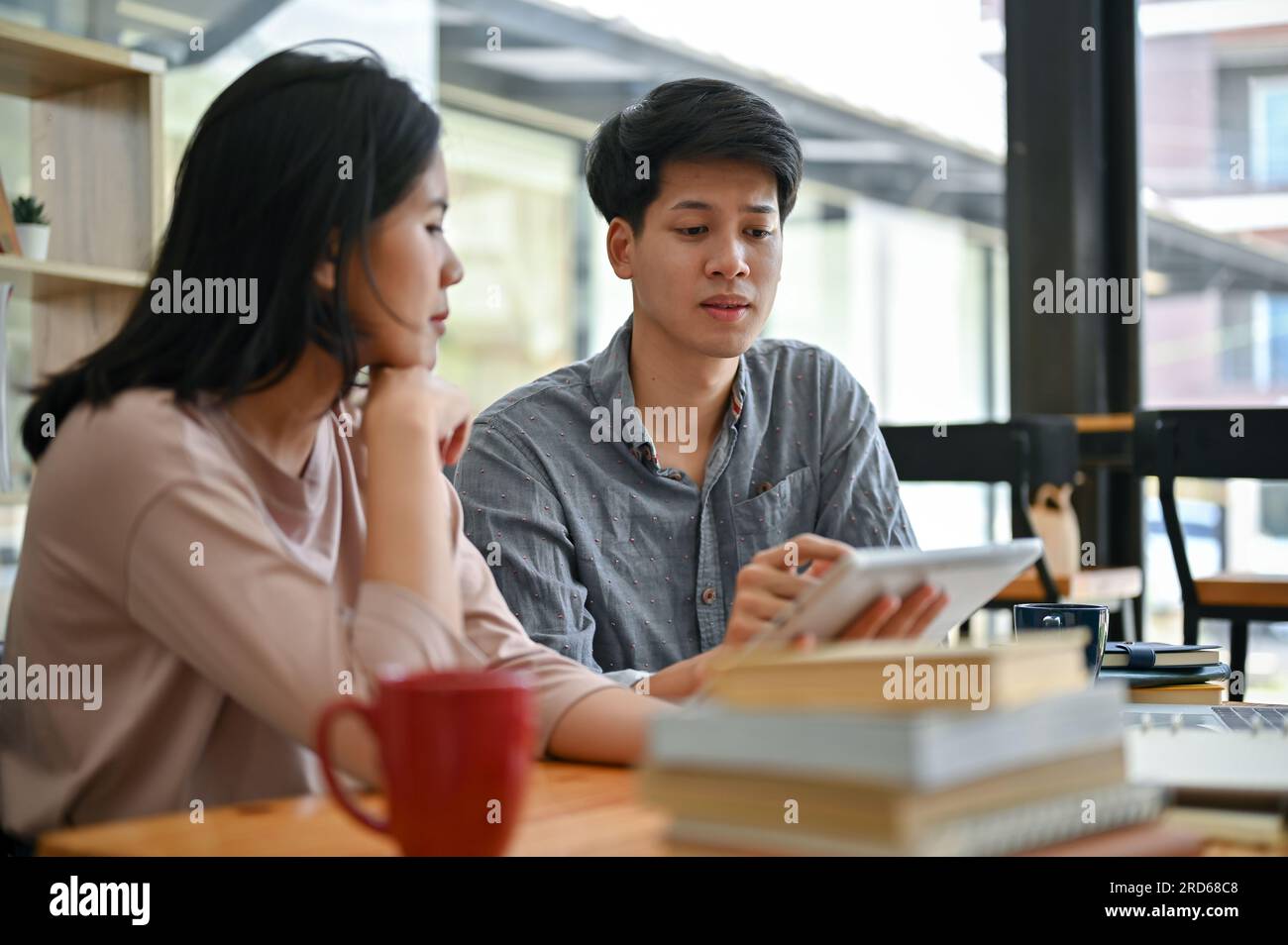 A smart and focused Asian male college student tutoring and helping his ...