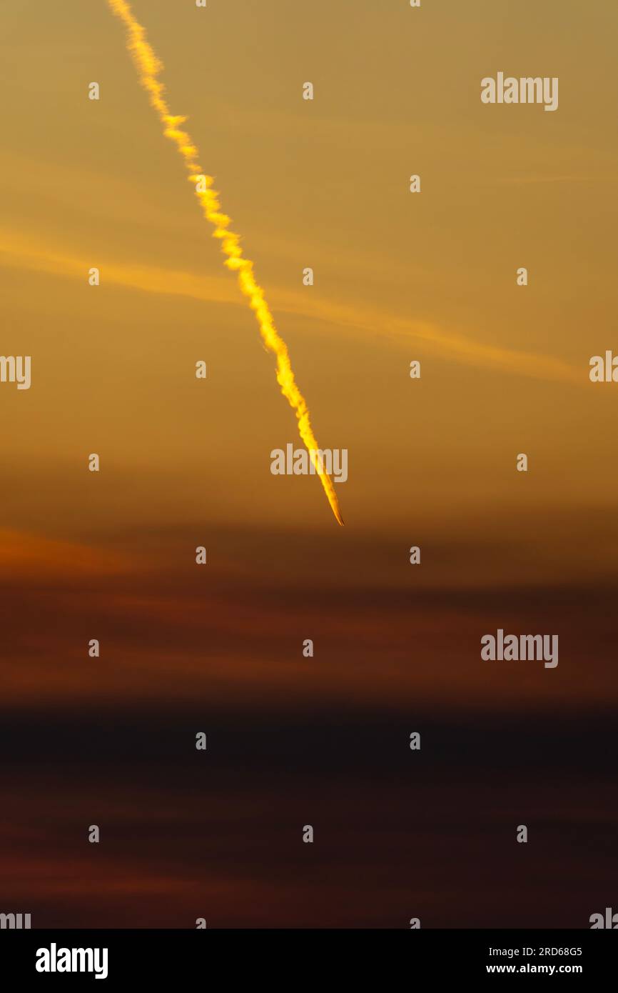Airplane vapor trail (contrail) across the golden sky at sunset Stock ...