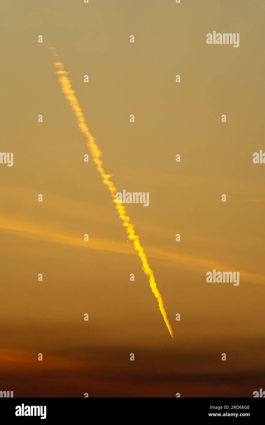 Airplane vapor trail (contrail) across the golden sky at sunset Stock ...