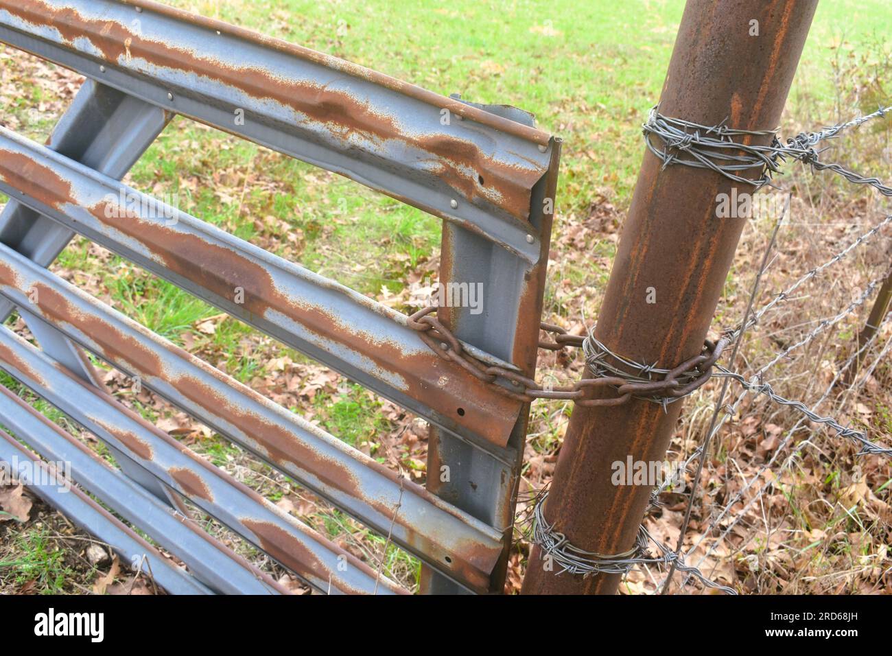 An old metal gate is held closed by a chain connected to a rusty metal ...