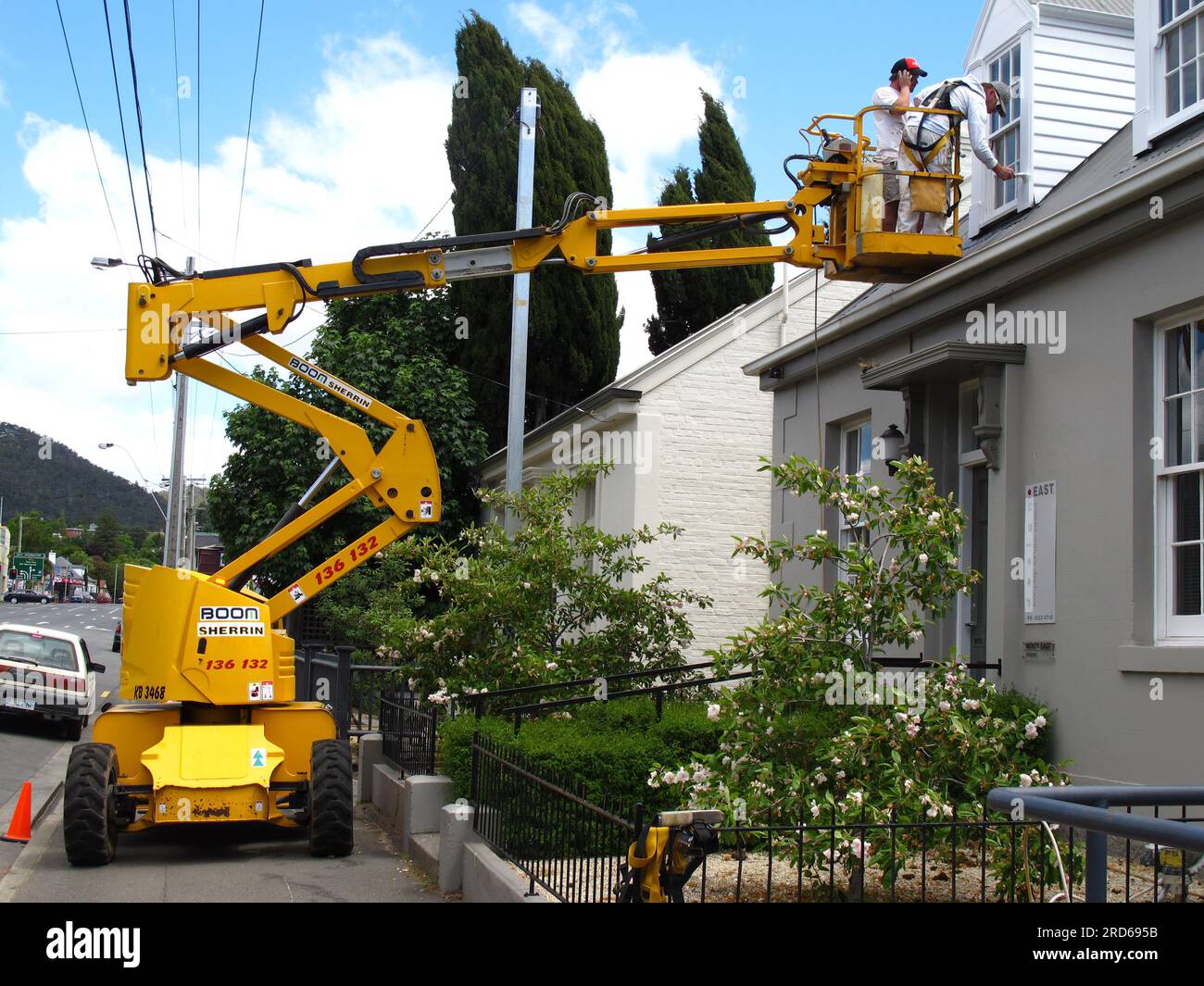 Painters using a mechanical scissor lift to pain the upper floors of a ...