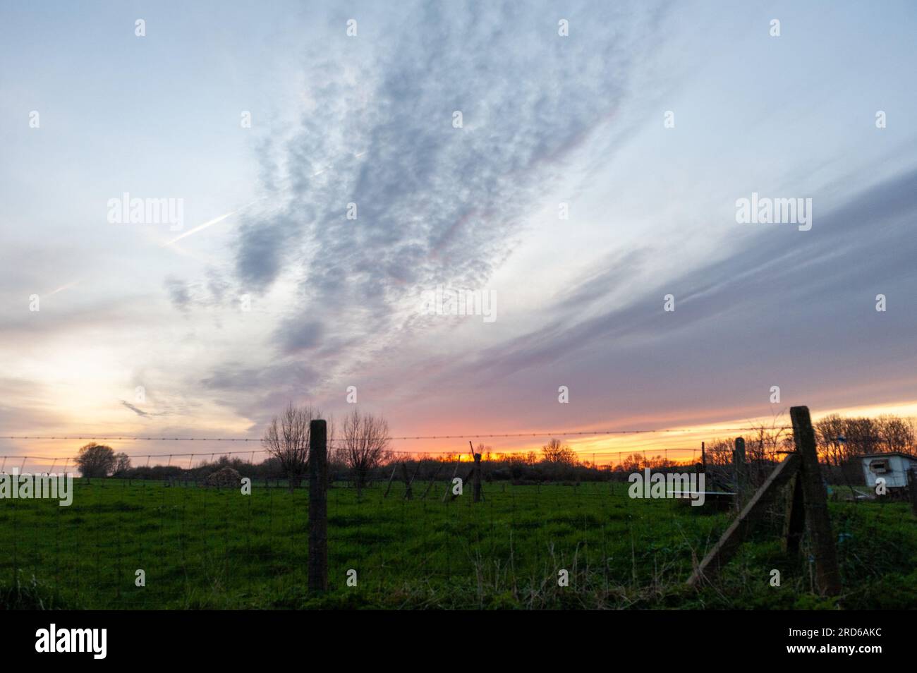 The setting sun in the flemish country side colors the sky intensely ...