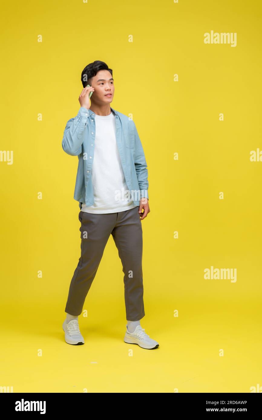 Full length shot of man walking and using talk smartphone isolated on ...