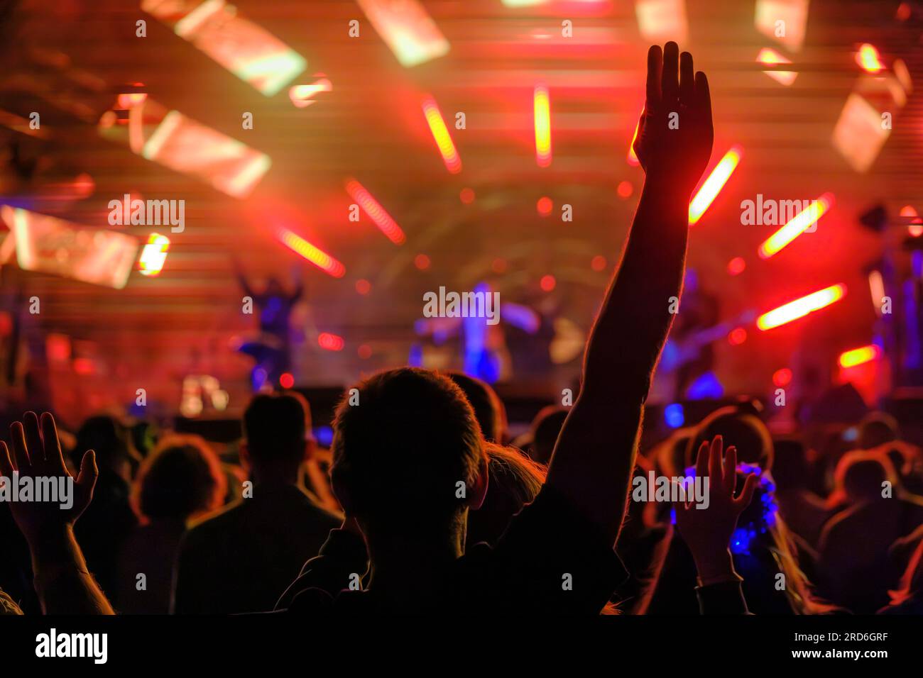 Back view of anonymous crowd of fans raising arms while dancing in ...