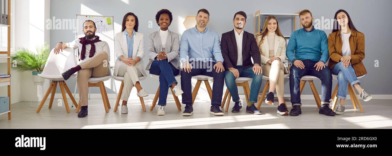 Company employees pose for publicity photo in open poses. Women sit ...