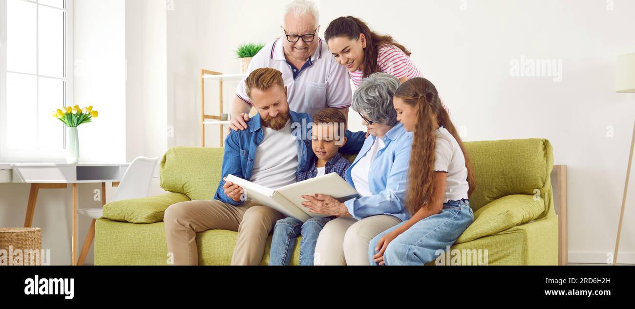 Happy family parents, kids, grandparents look at family photo album ...