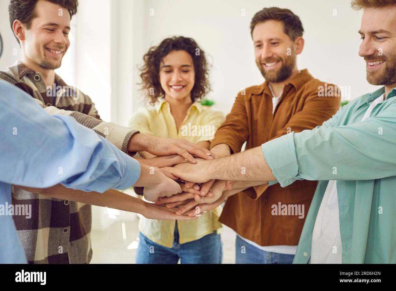 Happy smiling people friends putting their arms together in a stack ...
