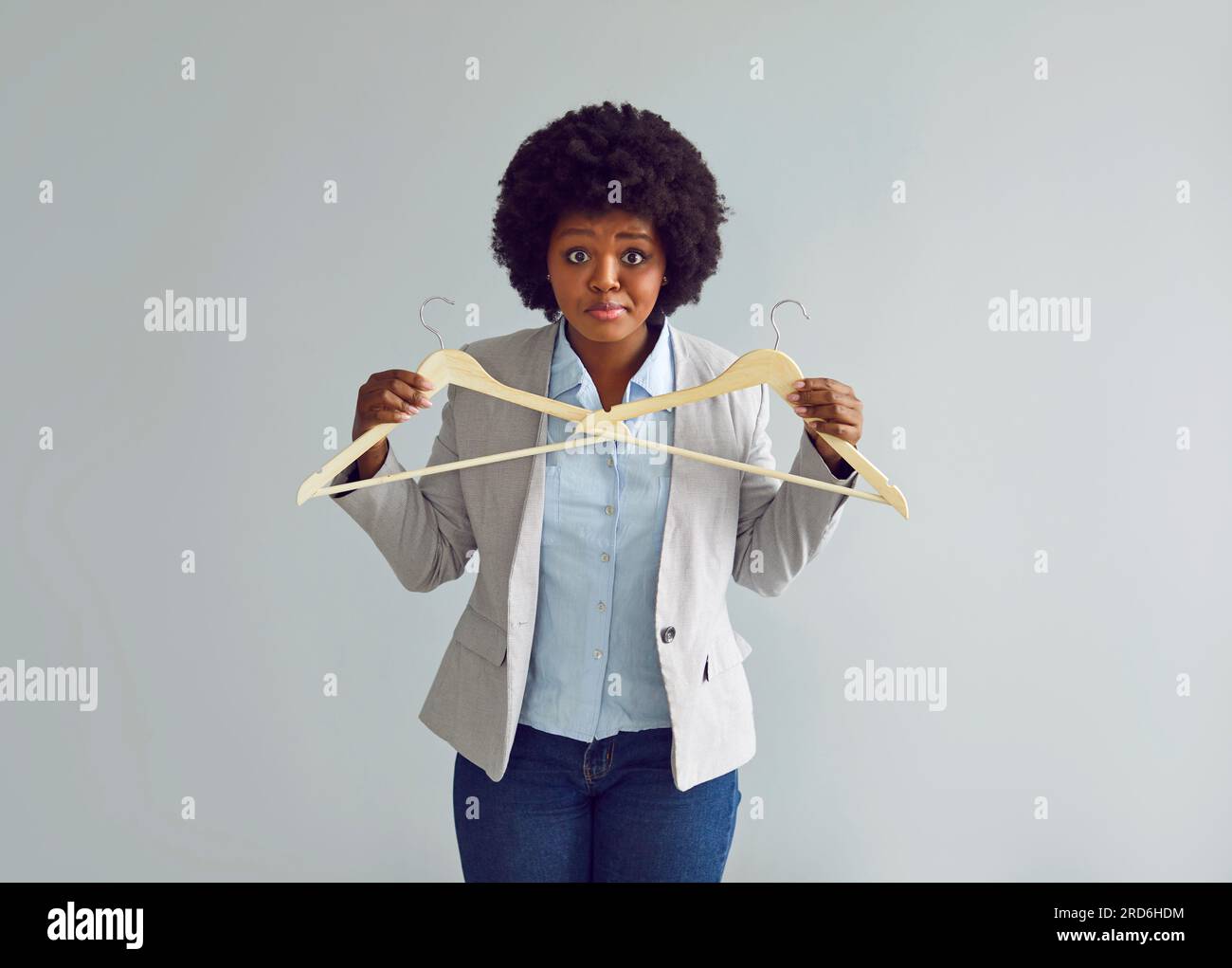 Funny young African American woman with empty clothes hangers has ...
