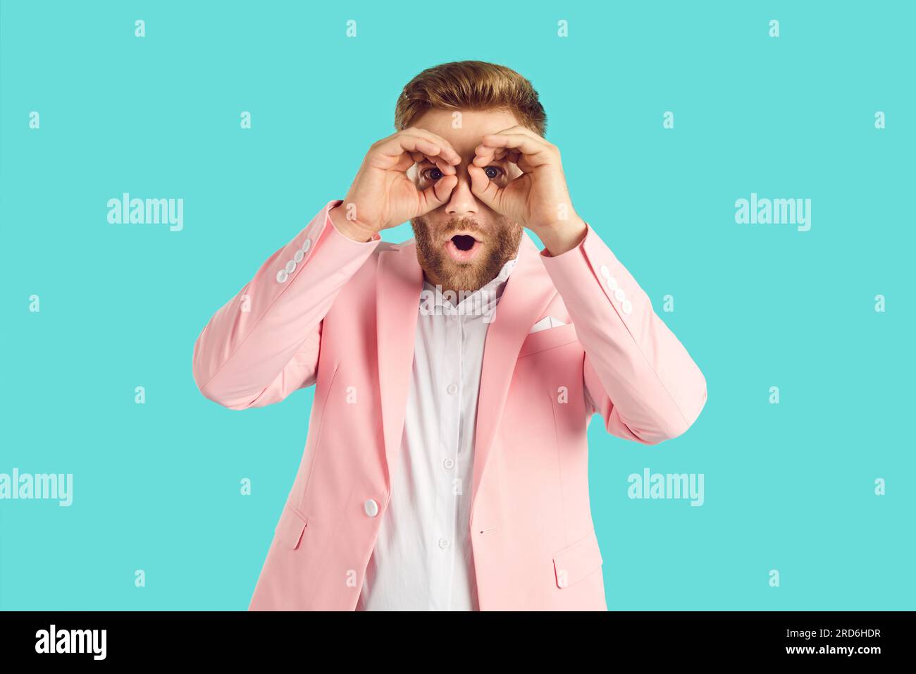 Funny, surprised young man is looking at something through binocular ...