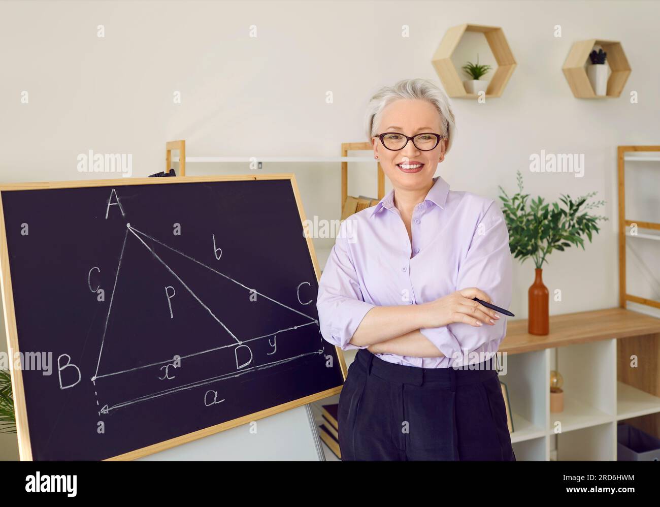 Portrait of happy smiling maths teacher standing by chalkboard in ...
