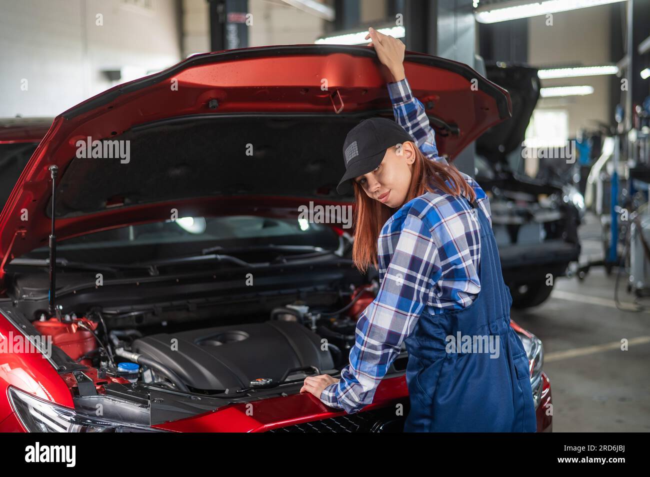 Woman auto mechanic opens the hood of a car in a car service Stock ...