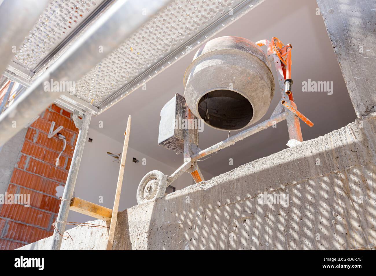 Shot from bellow on cement mixer machine placed on balcony of building ...