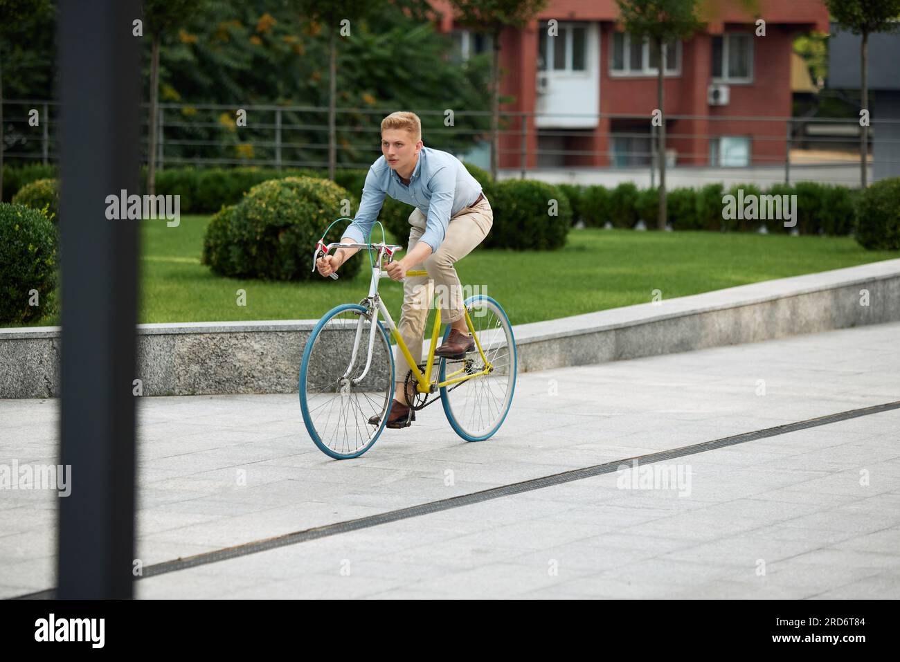 Stylish young man, office worker, employee riding to work on bike along ...