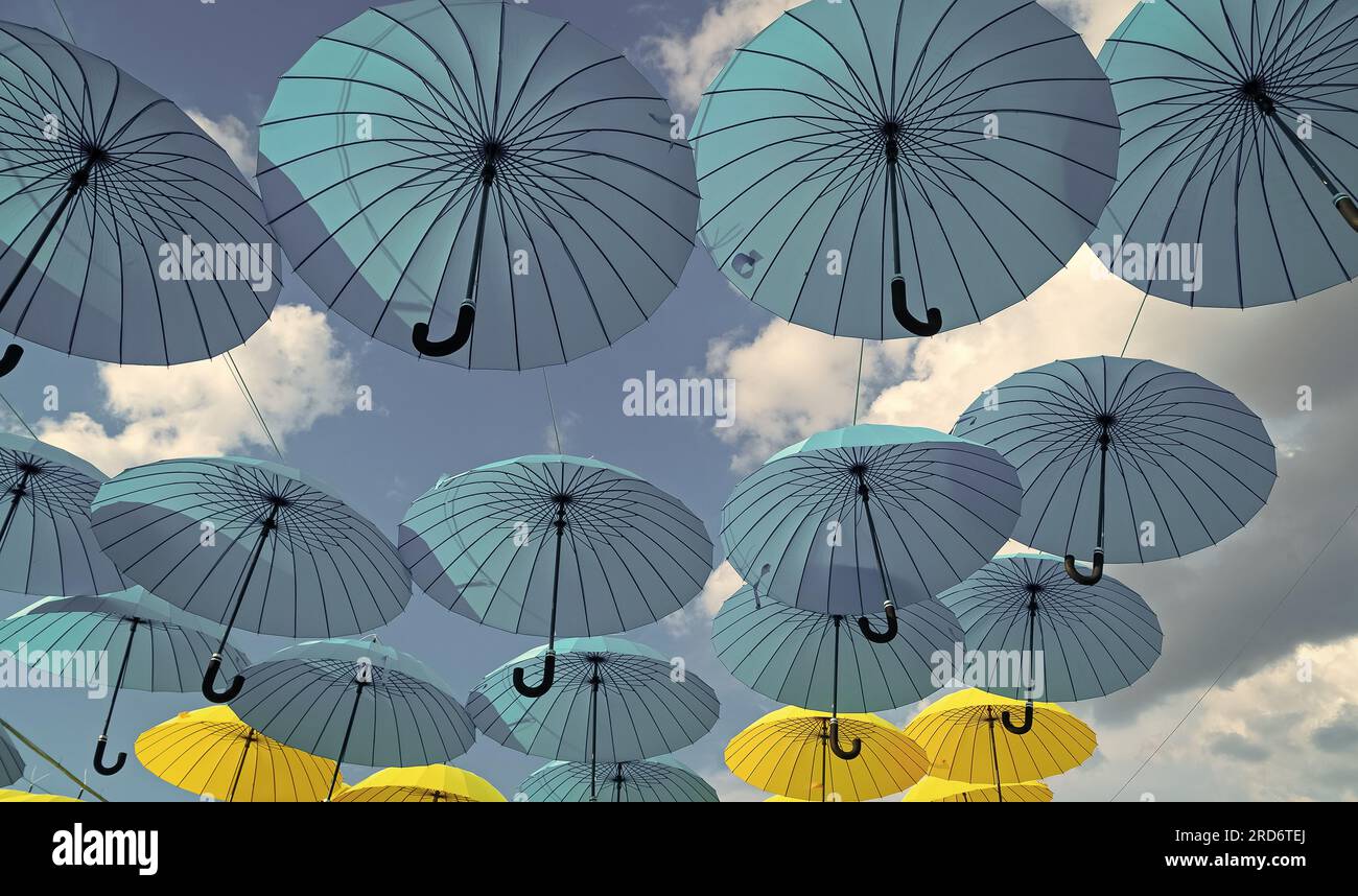 Blue and yellow umbrellas hanging bottom-up abstract sky background ...