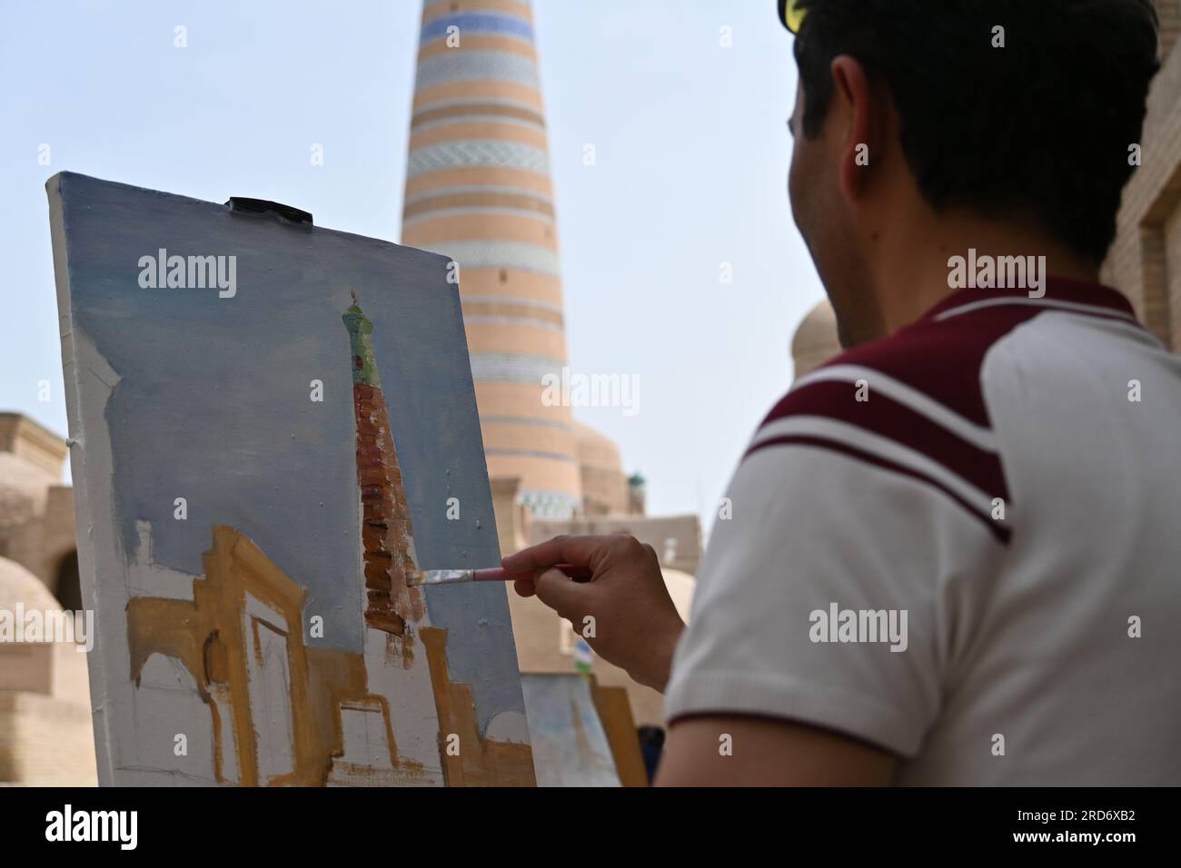 Close up of a uzbek man painting a minaret on a canvas in the city of ...