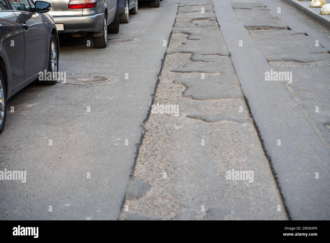 Broken asphalt road in city and untimely repairs in parking lot ...