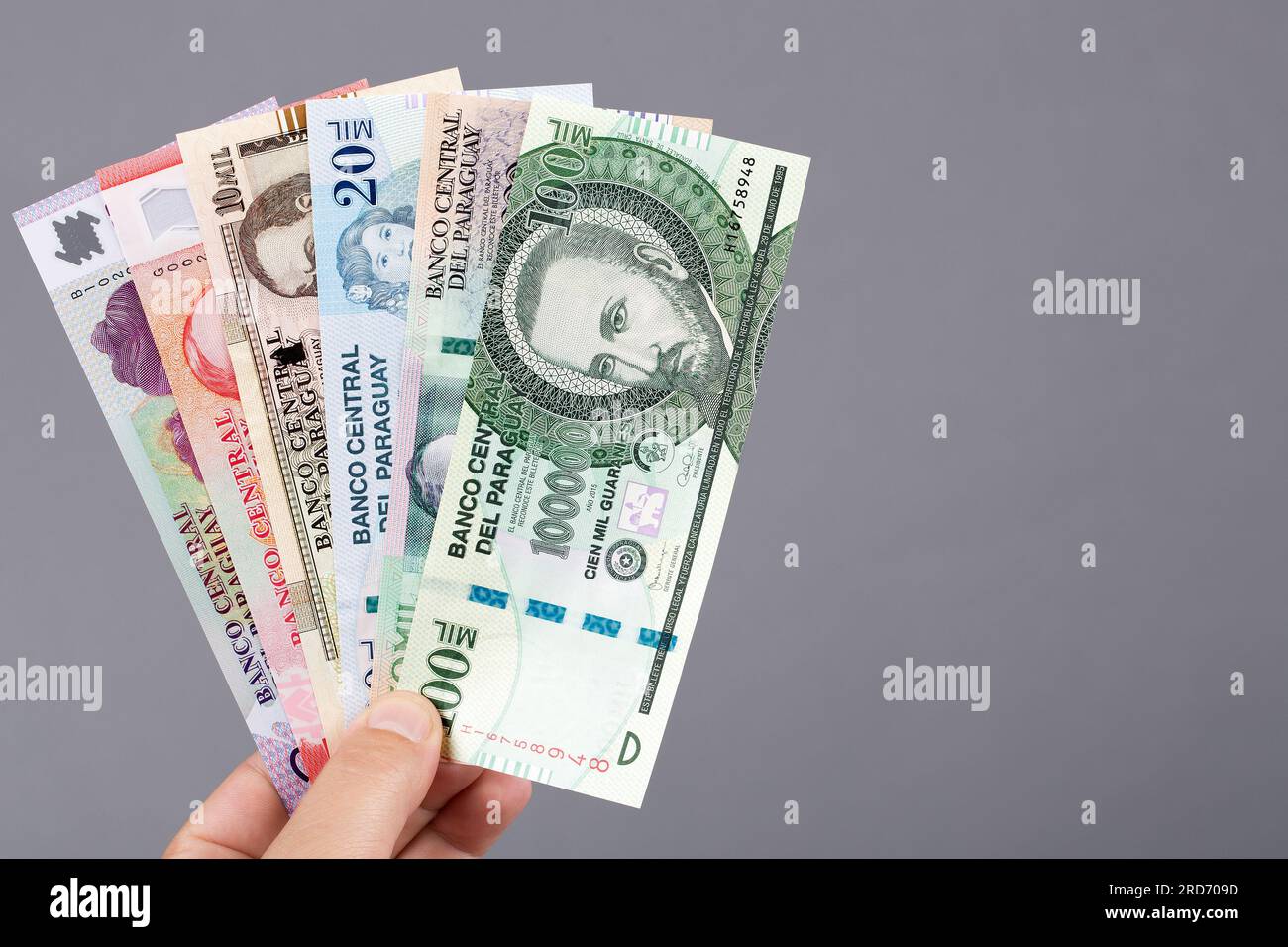 Paraguayan money - guarani in the hand on a gray background Stock Photo ...