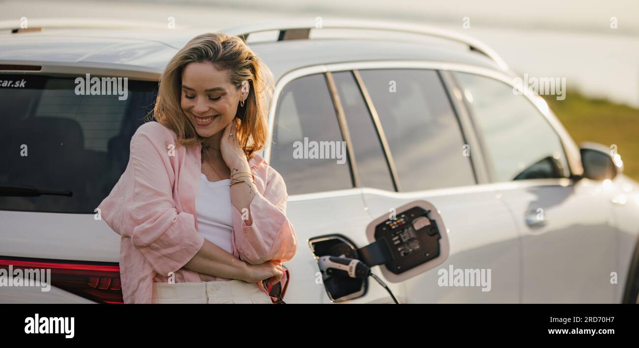 Woman charging her electric car, prepared for charging it sustainable ...