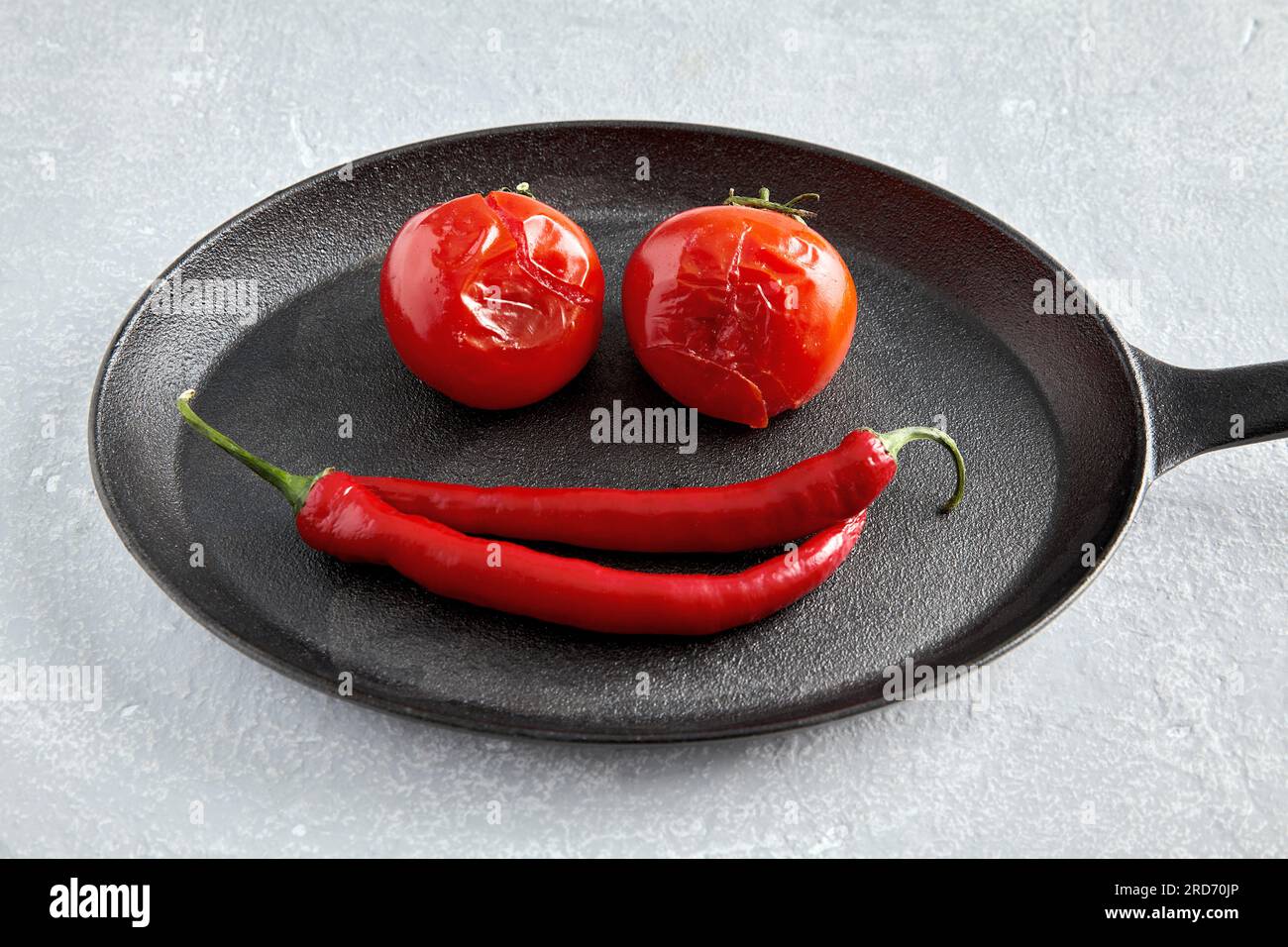 Roasted tomatoes and hot chili peppers are laid out in shape of smiling ...