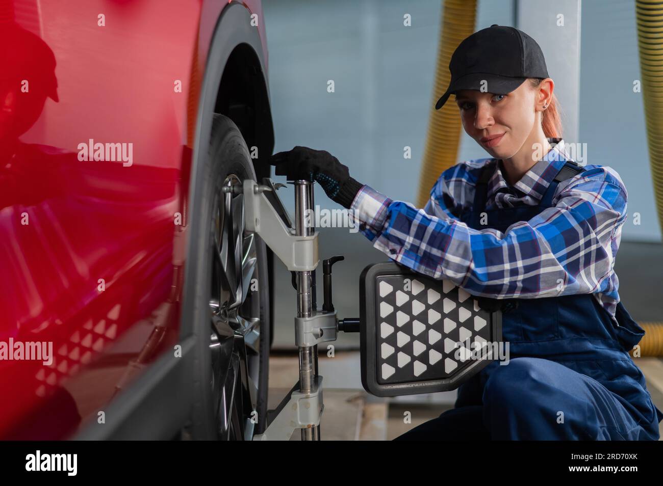 A female auto mechanic makes a camber. Woman working in a car service ...