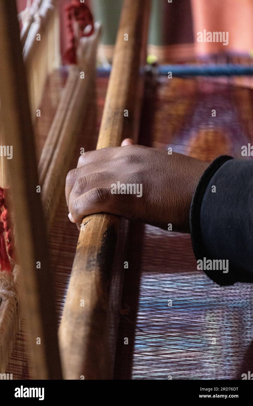 Hands of a carpet weaver as he weaves thread into geometric patterns ...