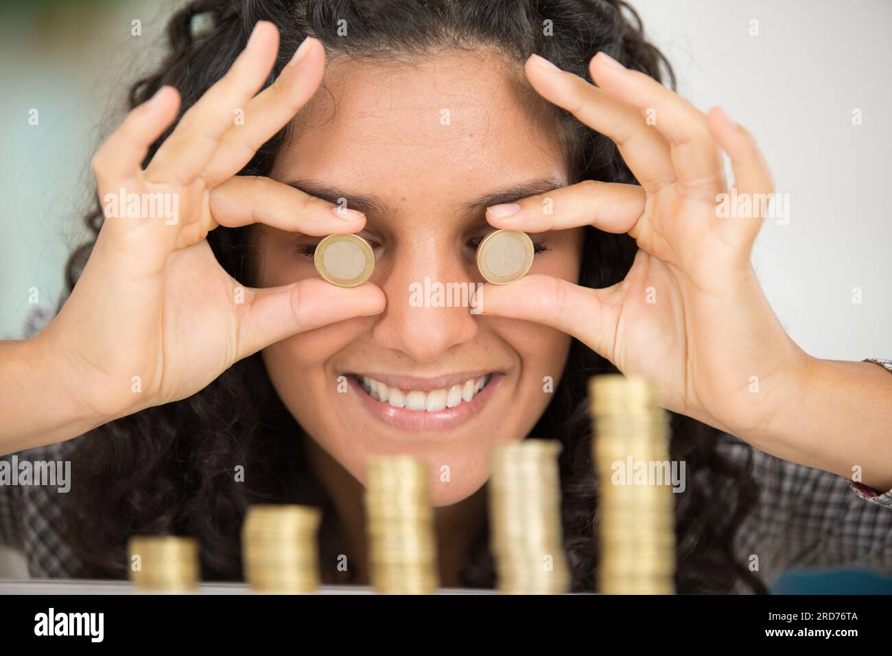 brunette woman facing camera stacking coins in piles on desk Stock ...