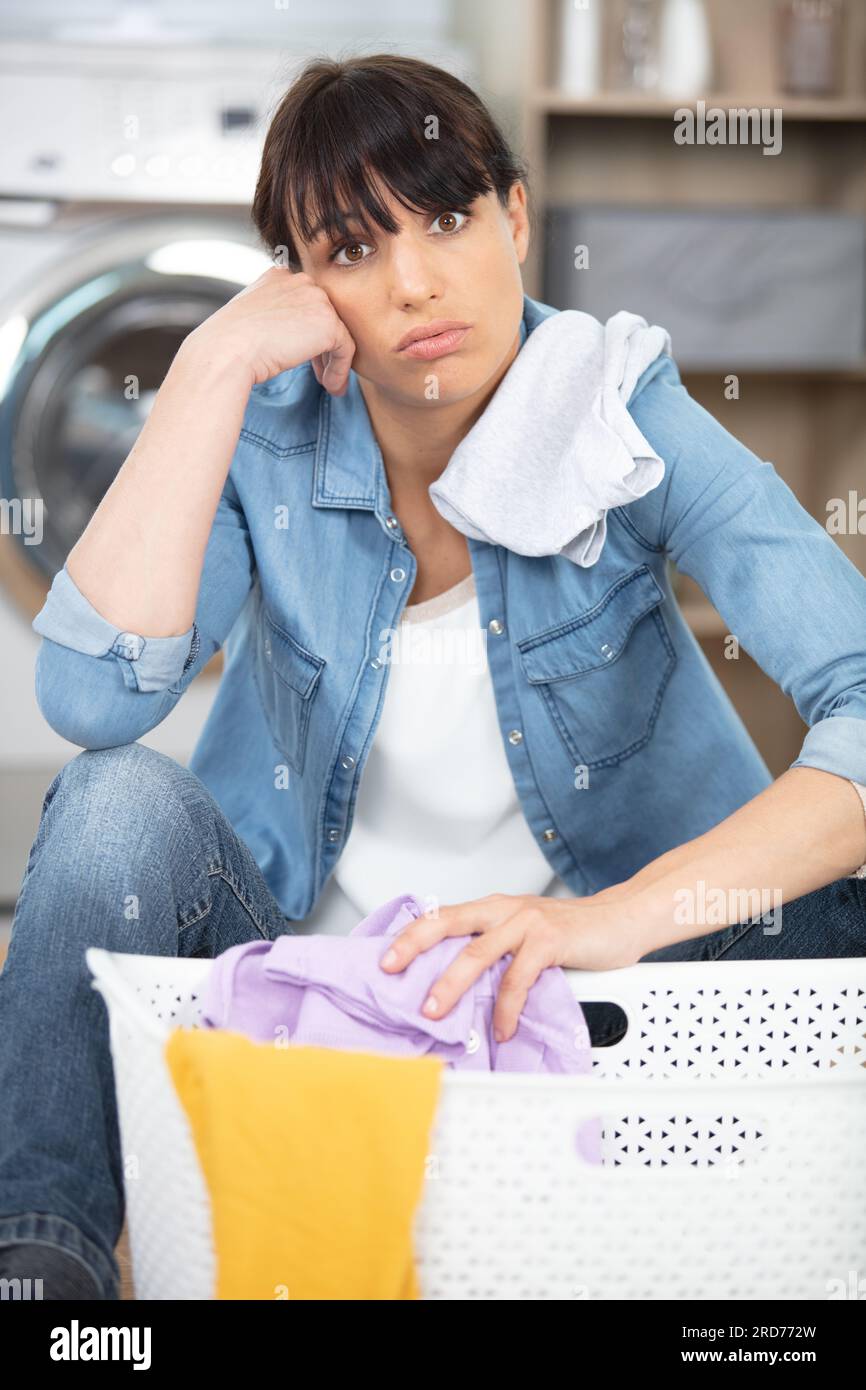 upset young woman with laundry sitting on the floor Stock Photo - Alamy
