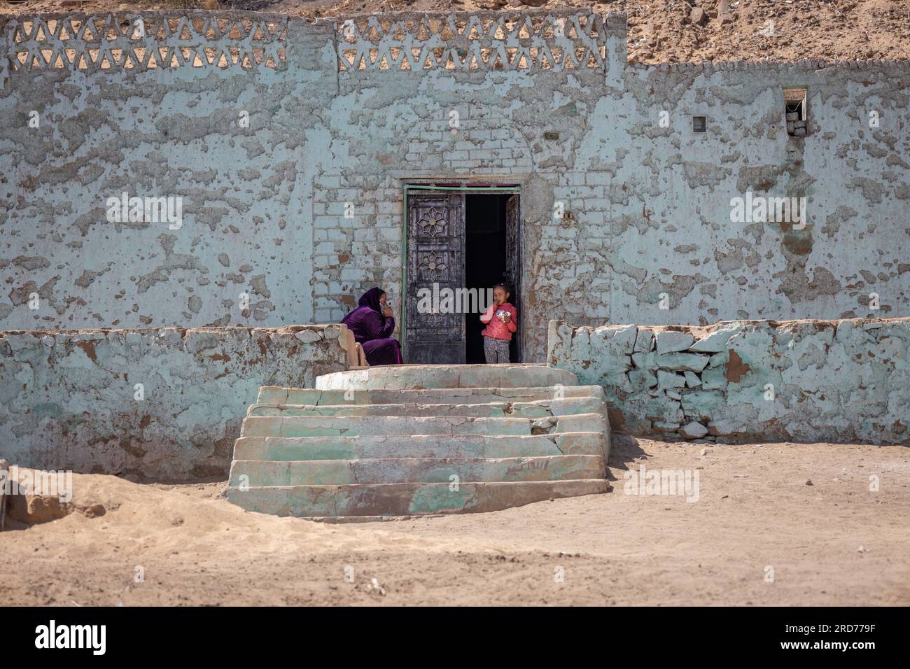 A mother spends time with her child on the doorstep of their home in a ...