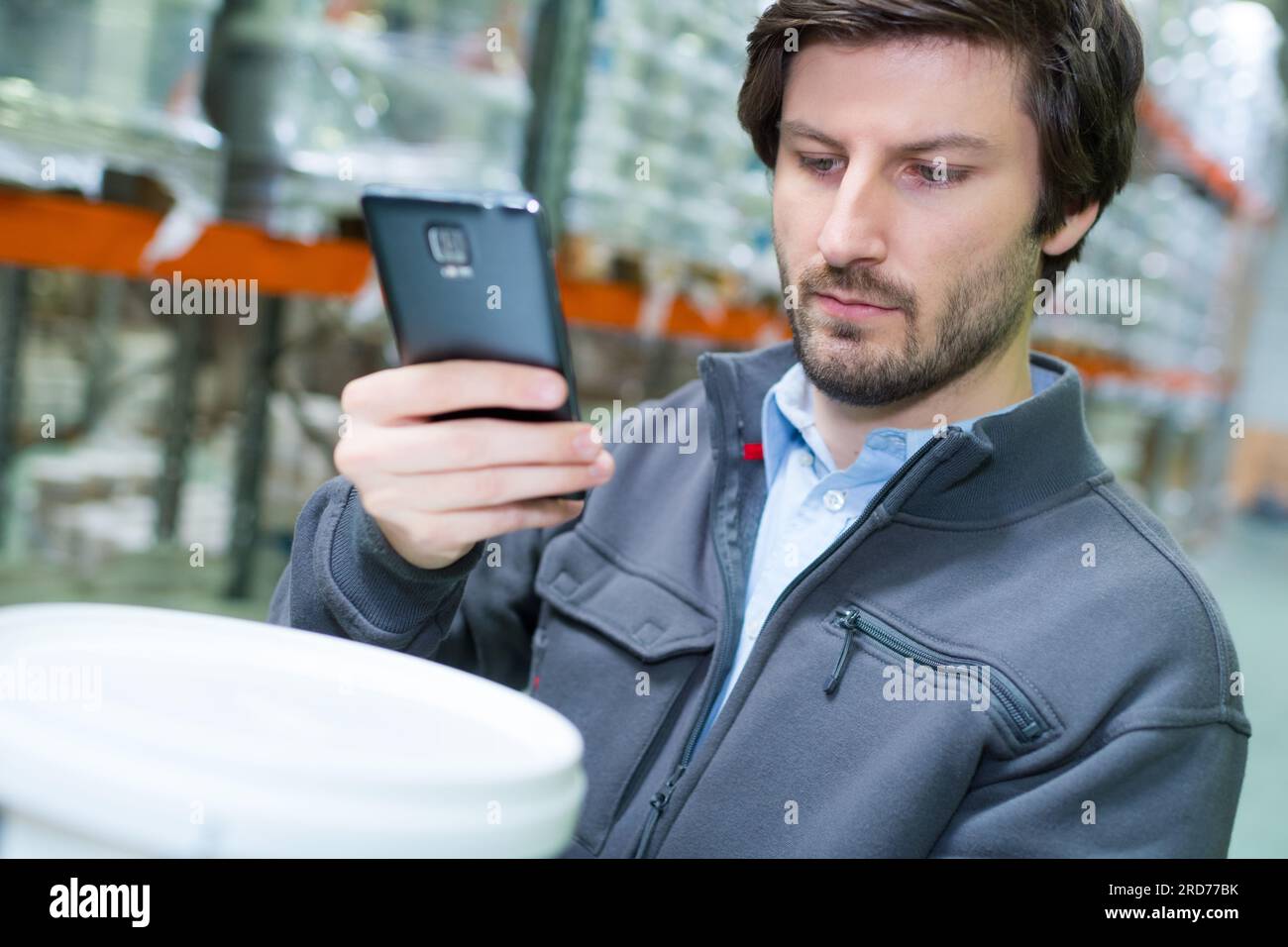 male seller checking a phone for type of paint Stock Photo - Alamy