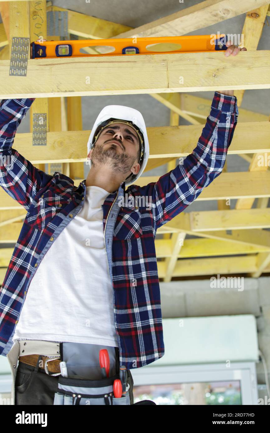 builder using spirit level on roof beam Stock Photo - Alamy