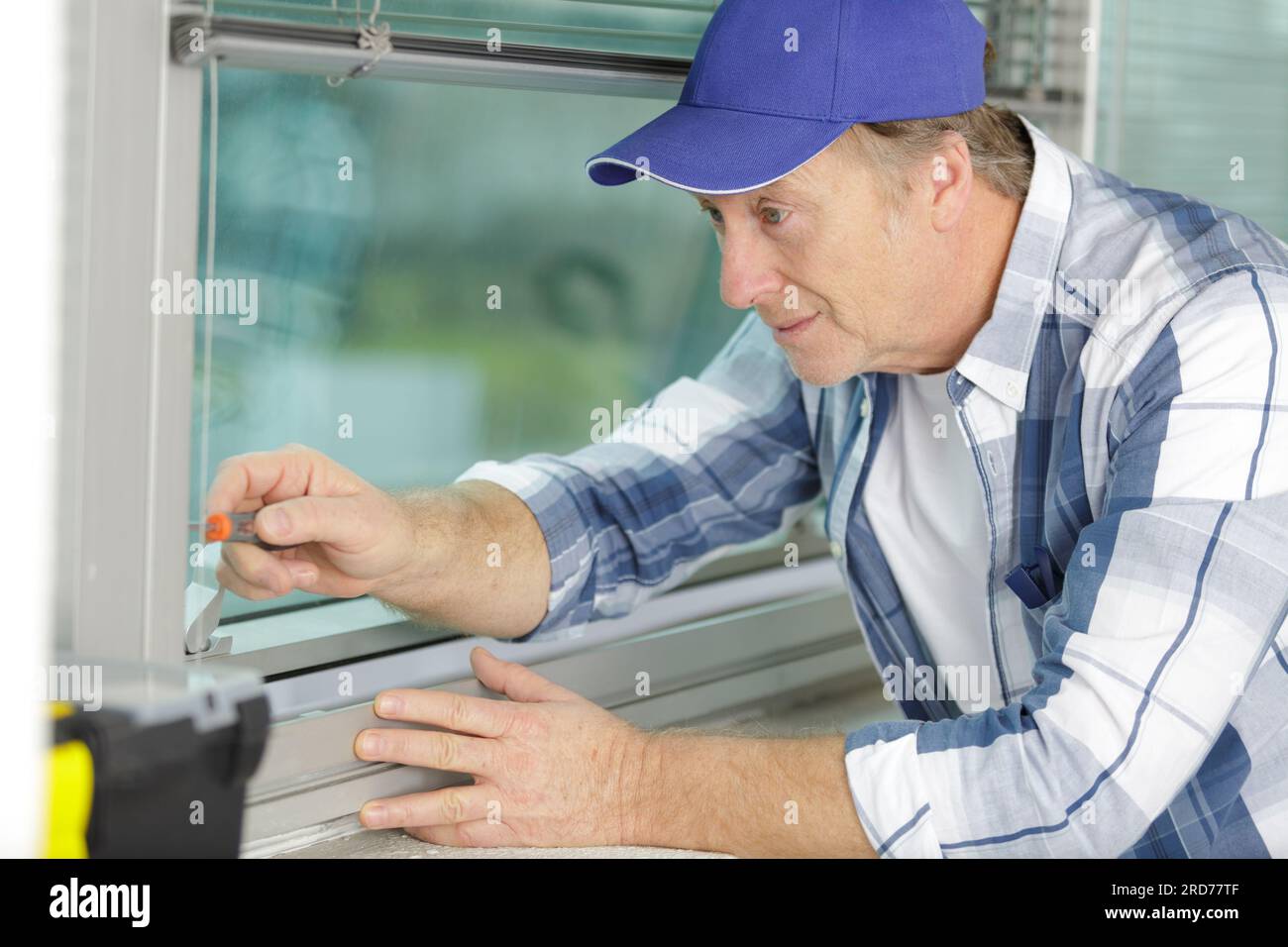 senior handyman repairing window with a screwdriver Stock Photo - Alamy