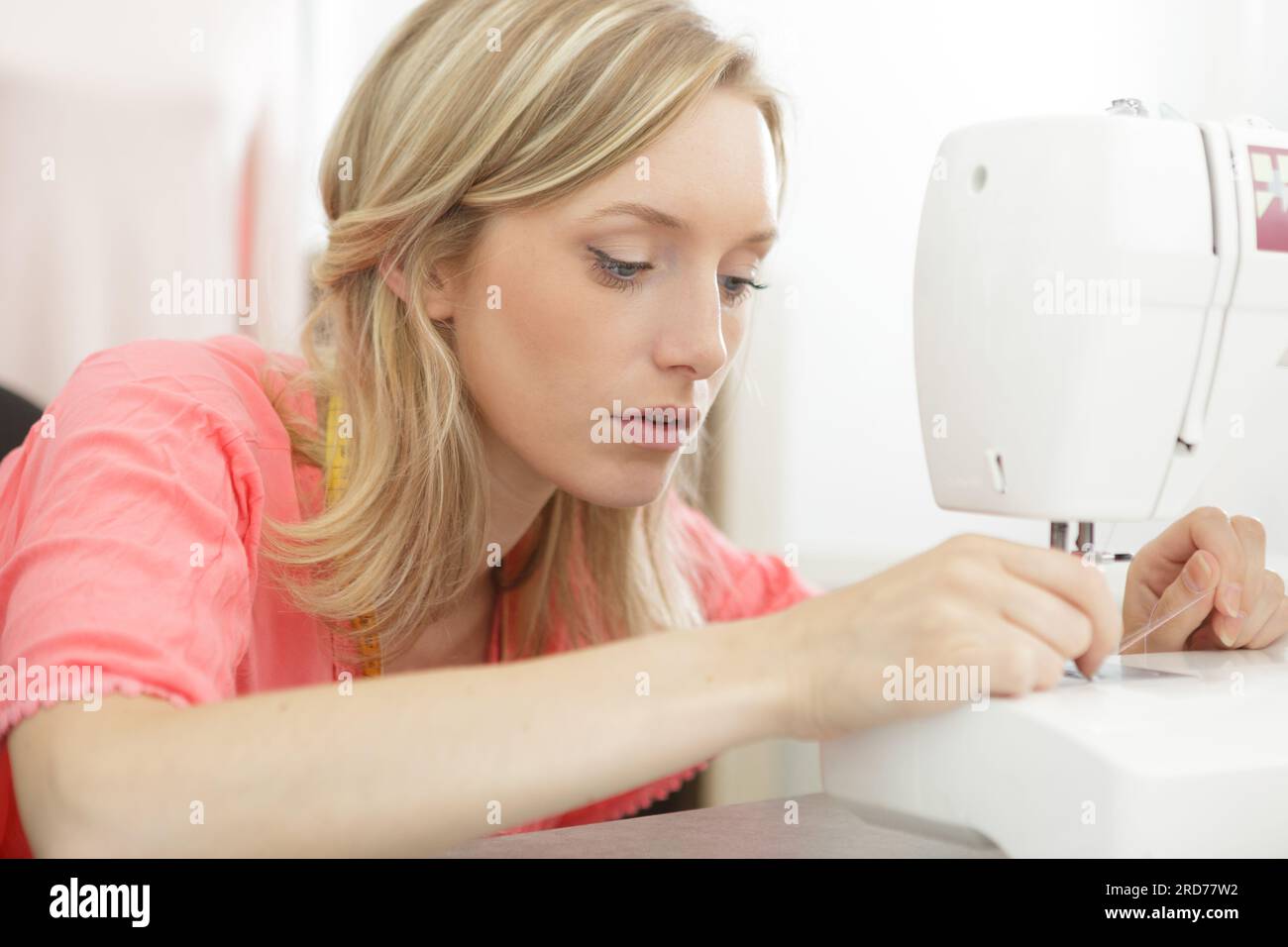 seamstress inserting thread to sewing machine needle Stock Photo - Alamy
