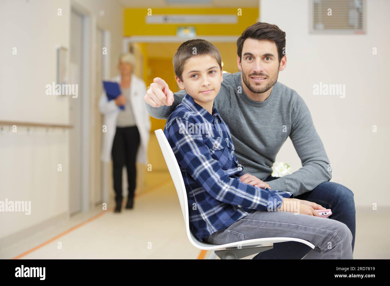 father with smiling son while waiting for doctor in hospital Stock ...