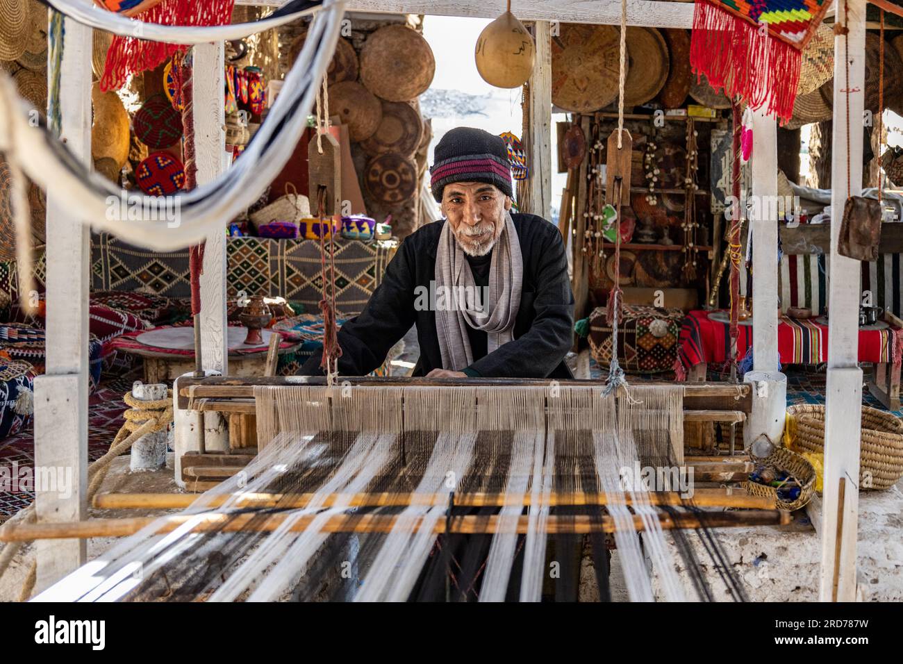 A carpet weaver flashes a smile to the camera as he demonstrates how ...