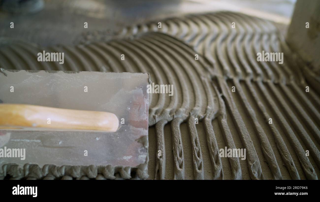 The adhesive is applied to the ceramic tile floor. Adhesive mortar for ...