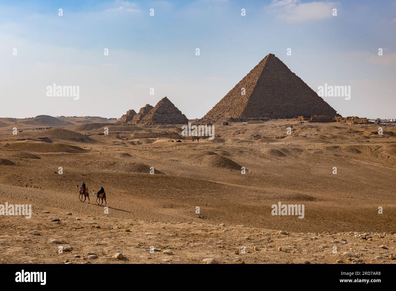 Men on camels cross the sands of the Sahara desert with the beautiful ...