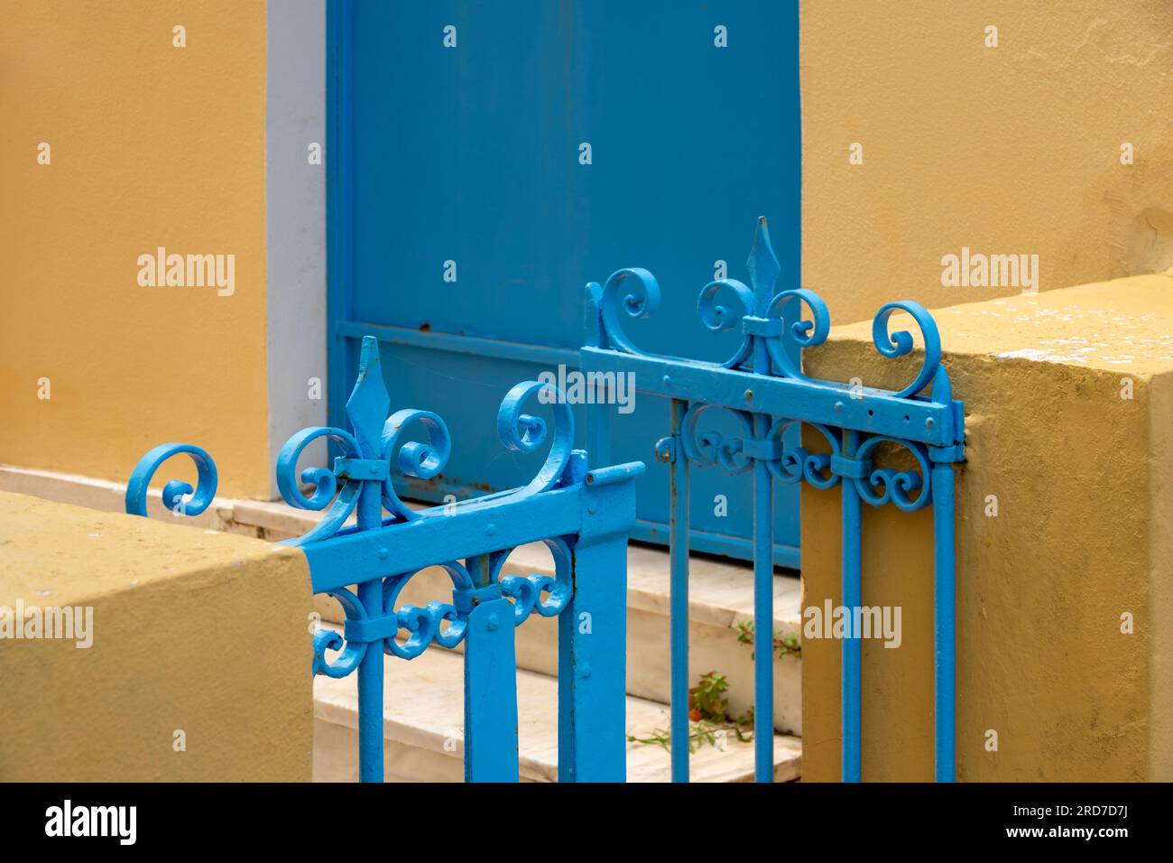 Two wrought iron and blue painted steel garden gates between concrete ...
